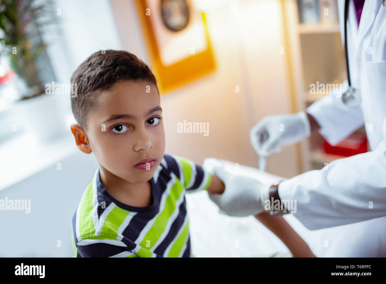 Dark-eyed preschool boy visiting pediatrician having injection Stock ...