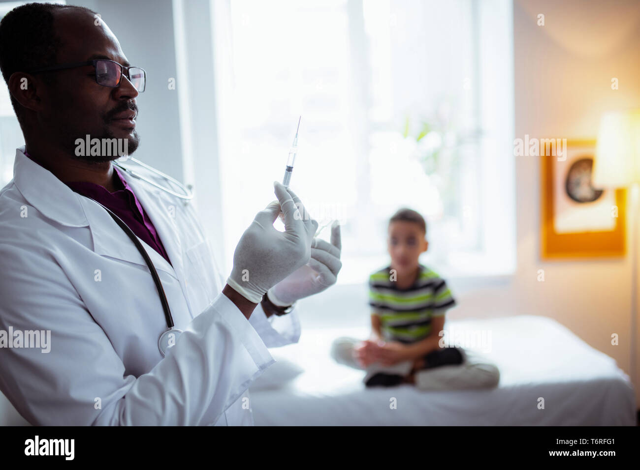 Pediatrician wearing gloves holding syringe before injecting boy Stock ...
