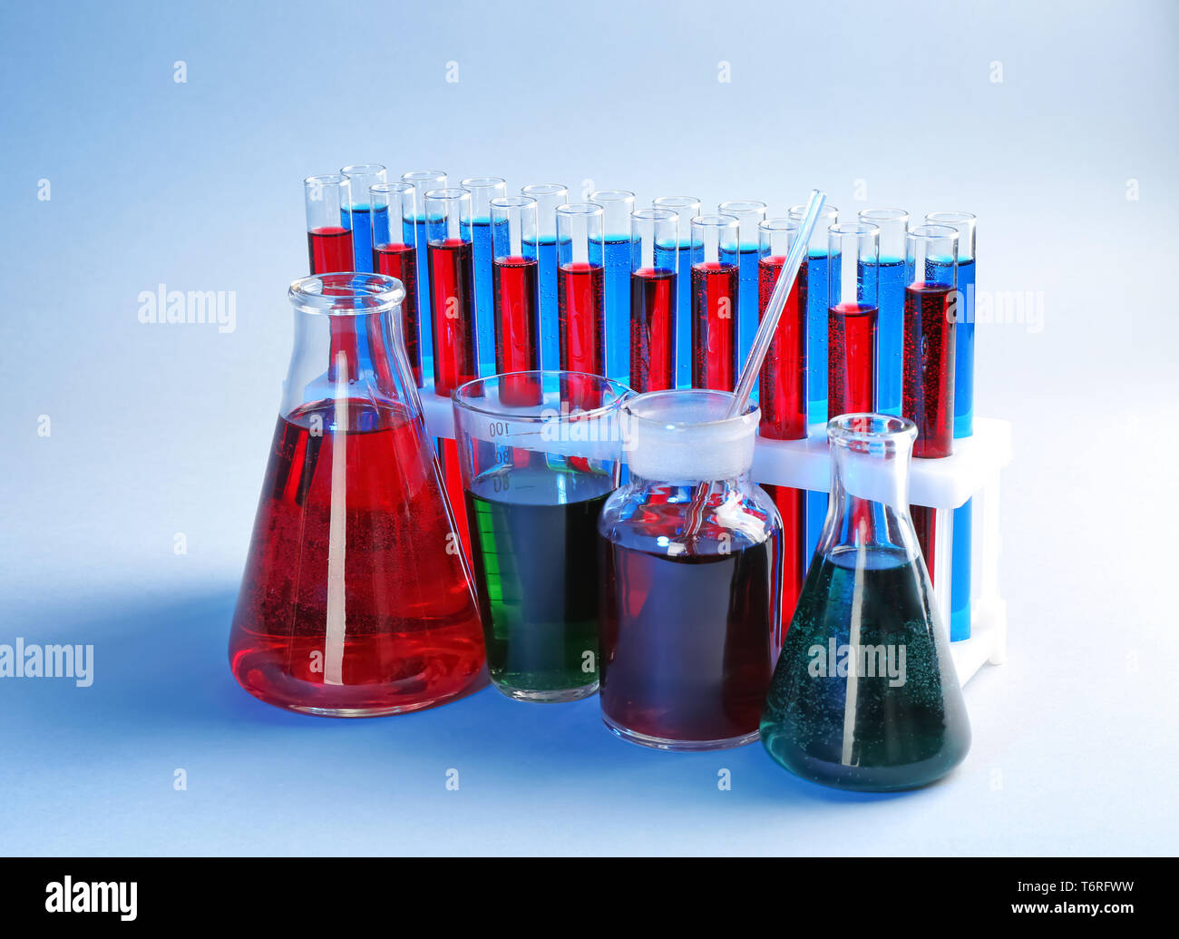 Chemical glassware with different liquids on color background Stock ...