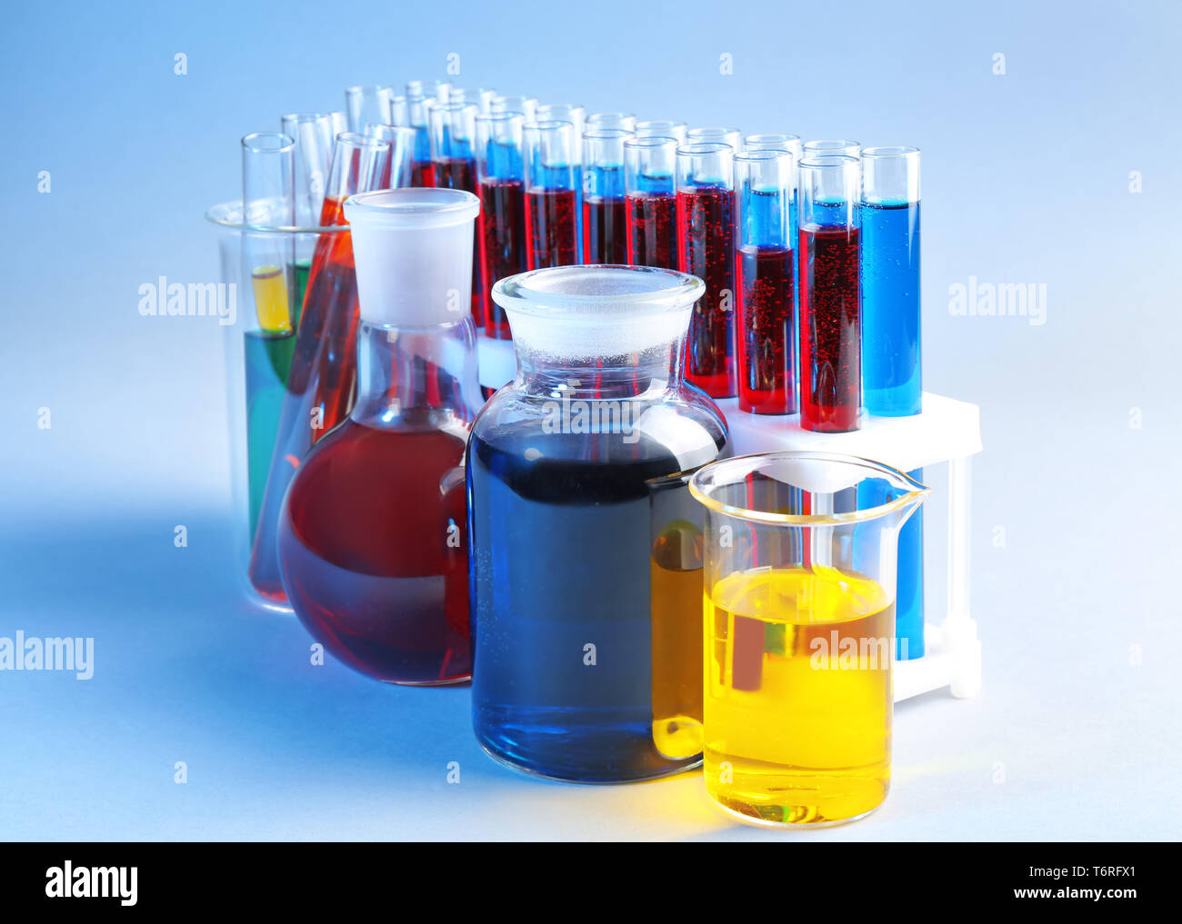 Chemical glassware with different liquids on color background Stock ...