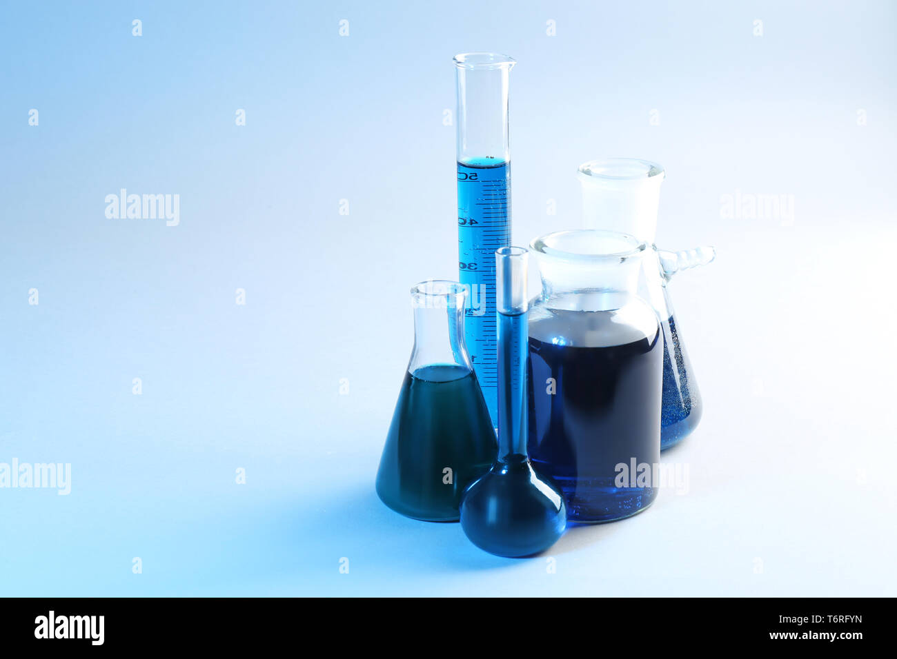 Chemical glassware with different liquids on color background Stock ...