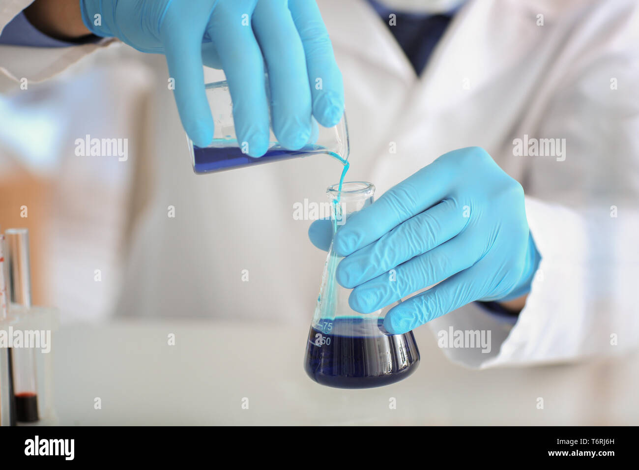 Scientist pouring sample into test flask in laboratory Stock Photo - Alamy