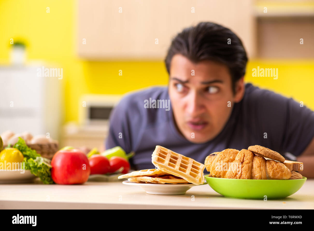 Man having hard choice between healthy and unhealthy food Stock Photo ...