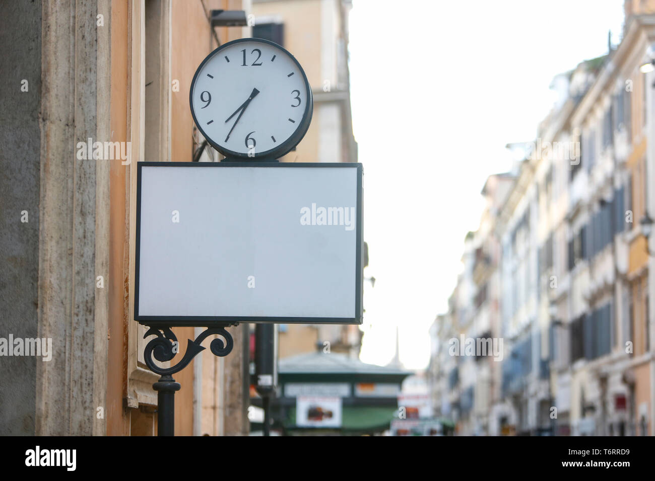 Street clock and empty rectangular blank sign on the street in the city ...