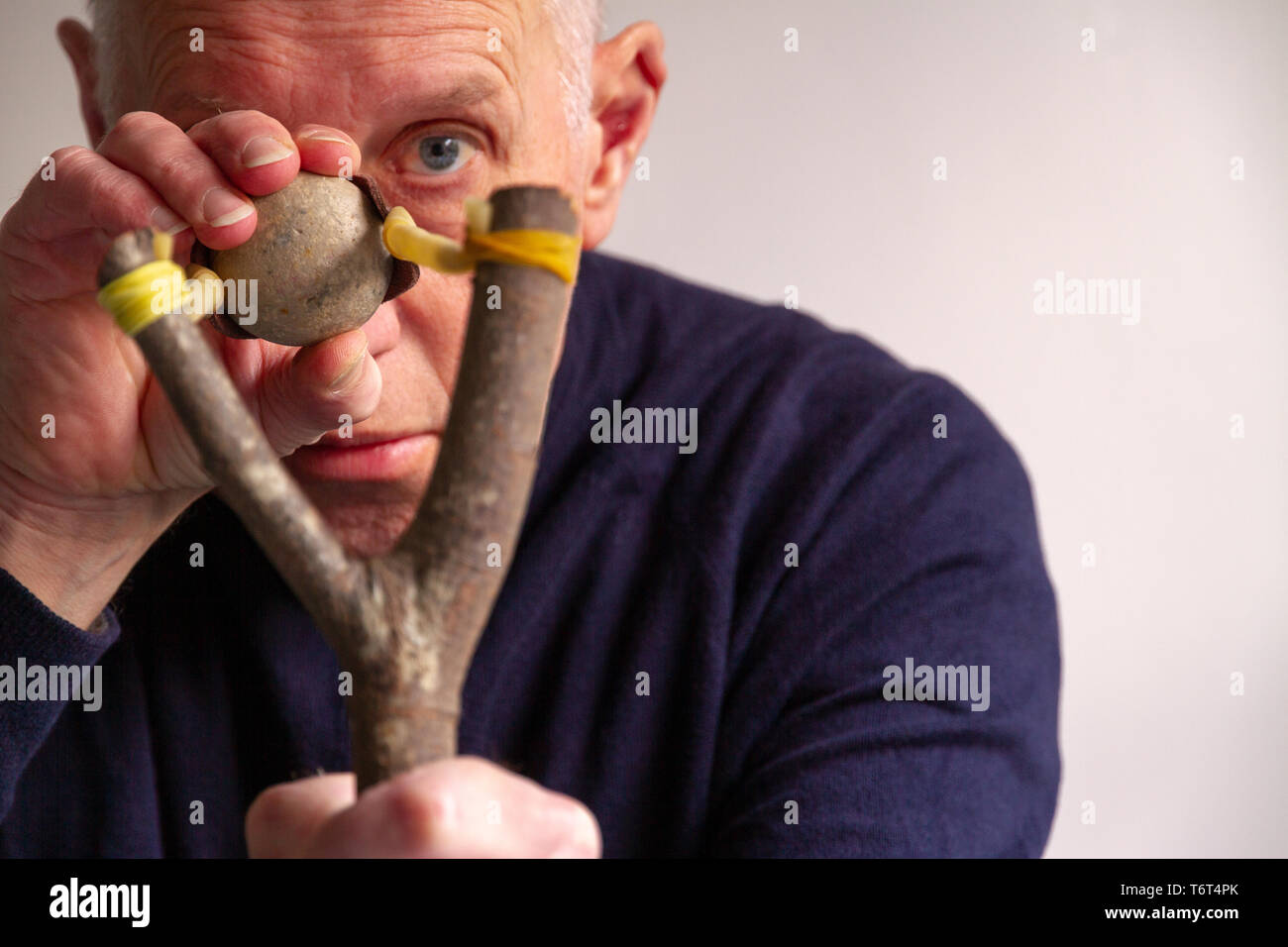 A man is aiming a homemade toy catapult at the camera. Space to one ...