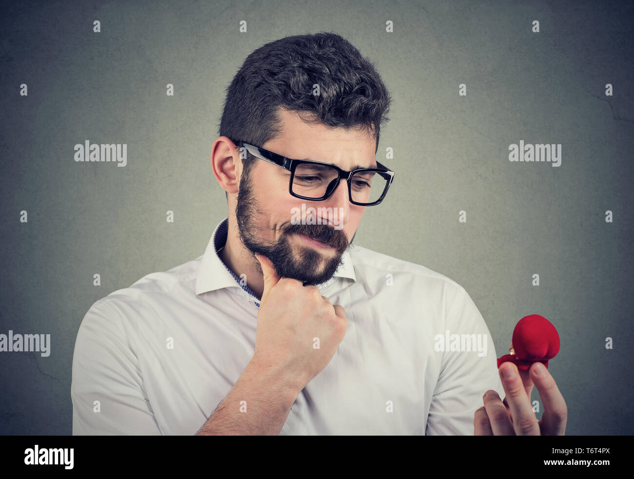 Confused young man looking at an engagement ring and has doubts Stock ...