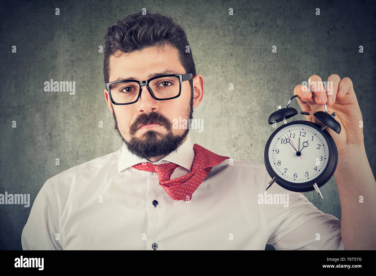 Sad overworked business man with alarm clock Stock Photo - Alamy