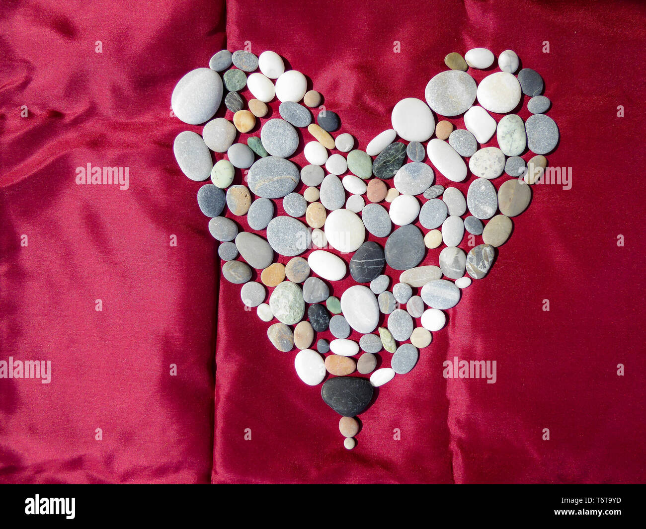 Heart of colourful beach pebbles on ruby background Stock Photo - Alamy