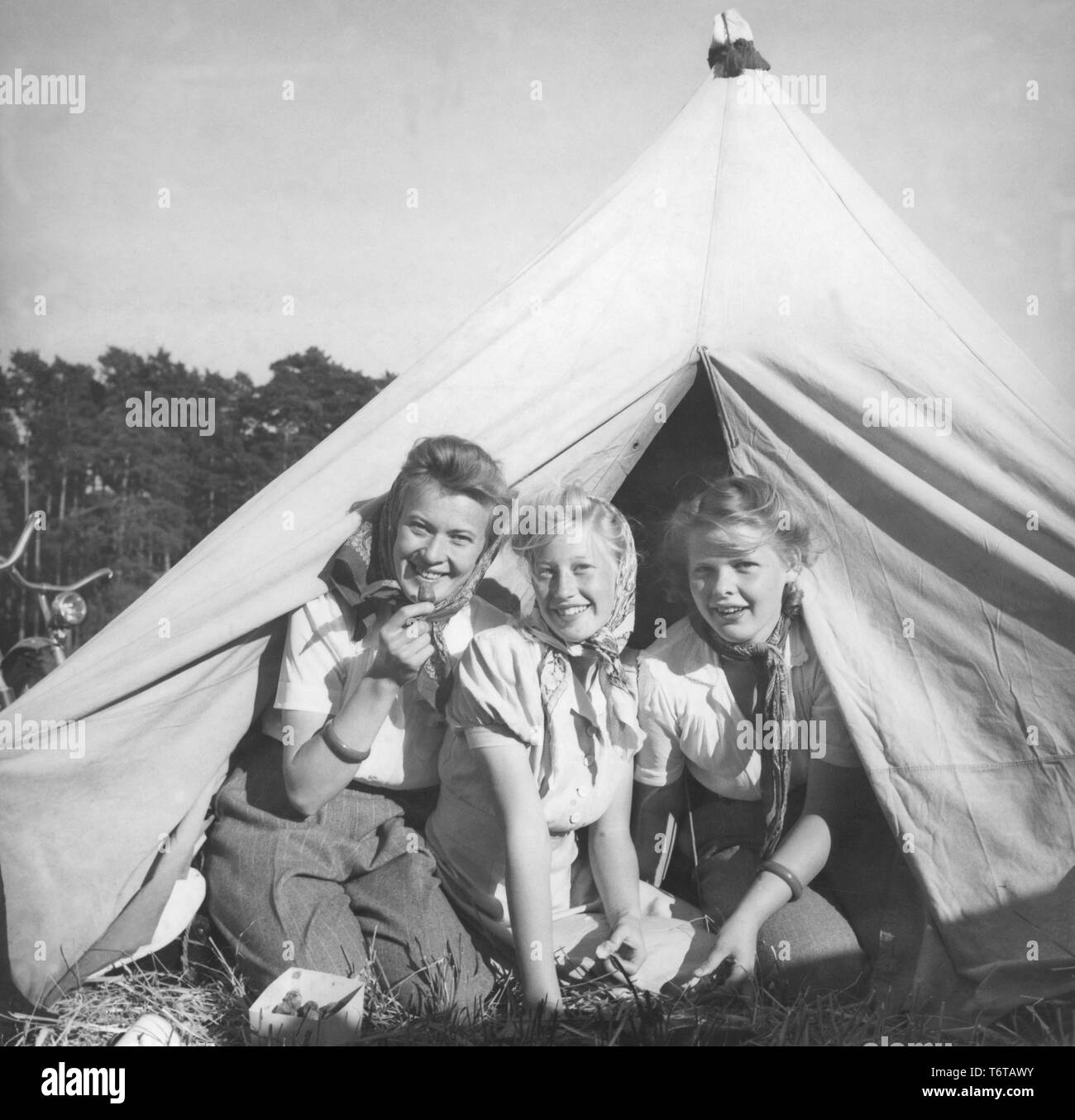 Camping in the 1940s. Three friends are sitting in the entrance of ...