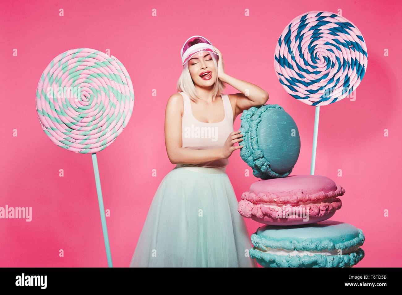 Beautiful girl posing with sweets at pink background Stock Photo - Alamy
