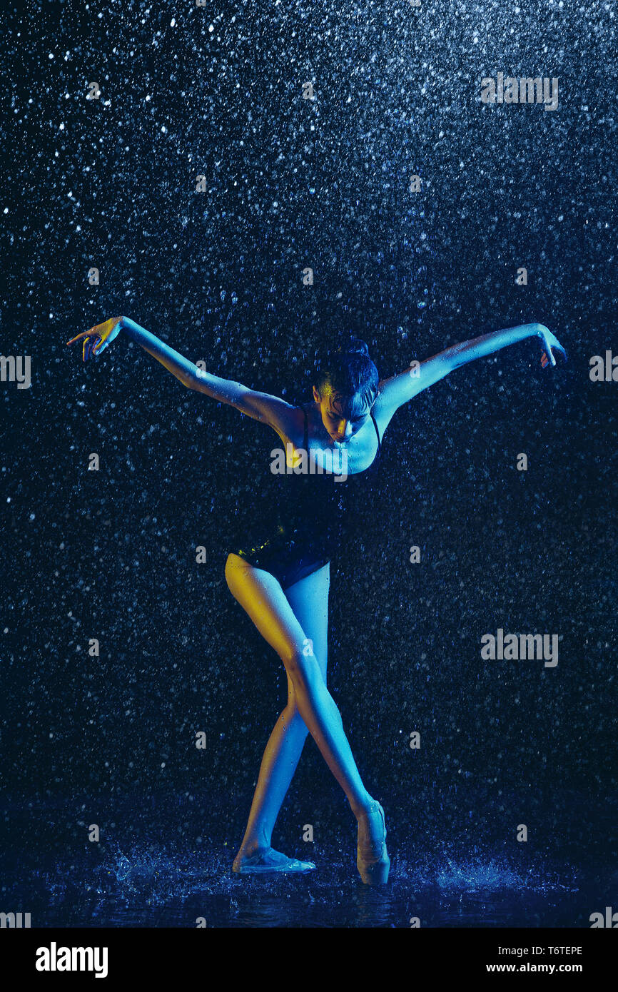 Young female ballet dancer performing under water drops and spray ...