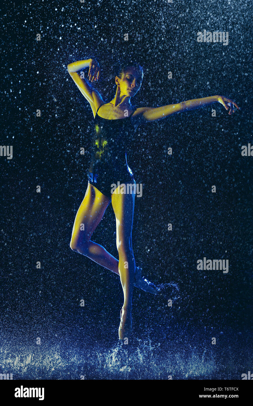 Young female ballet dancer performing under water drops and spray ...