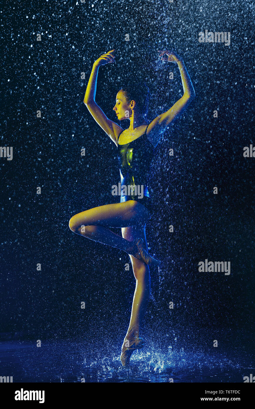 Young female ballet dancer performing under water drops and spray ...