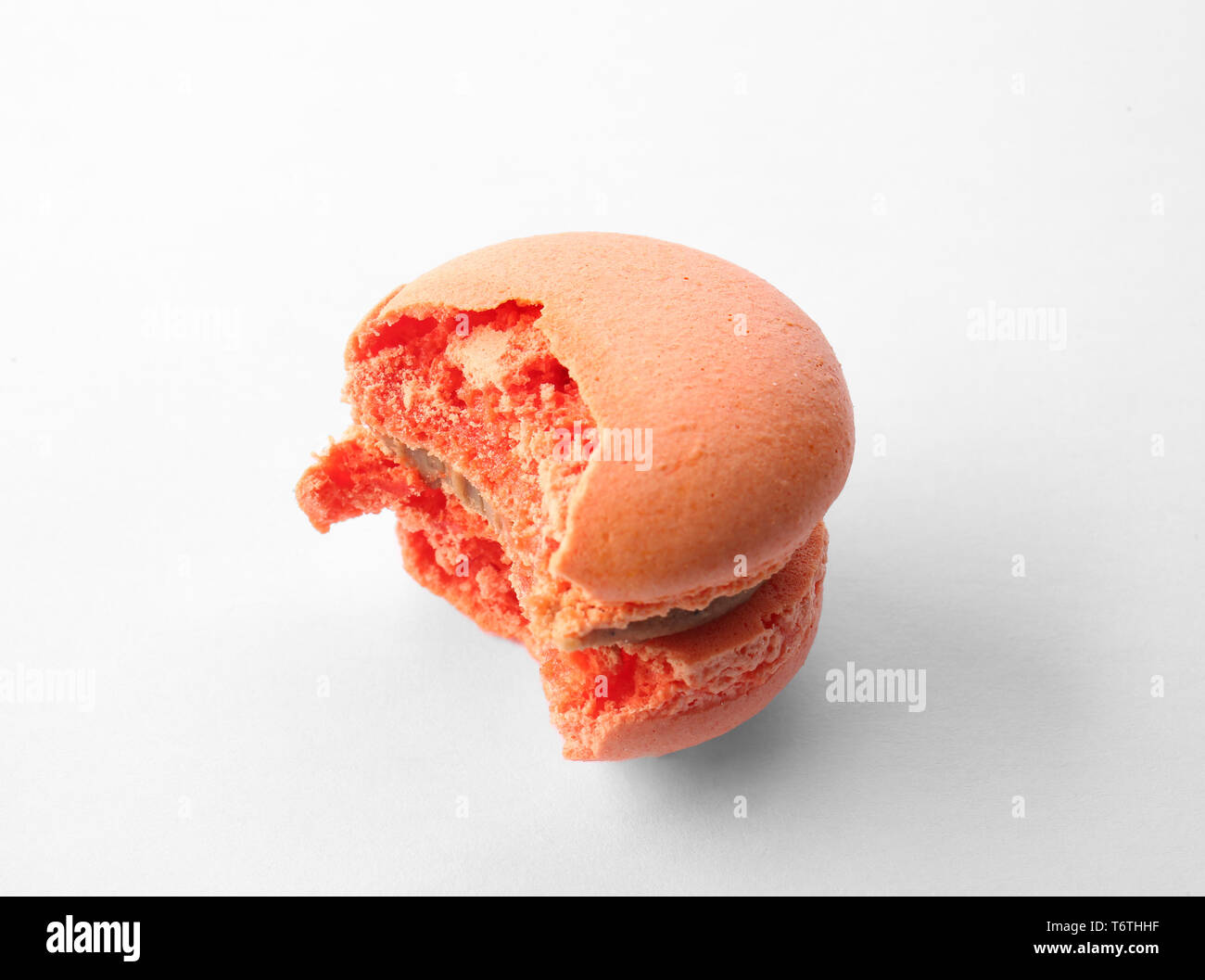 Tasty orange macaron with bite mark on white background Stock Photo - Alamy