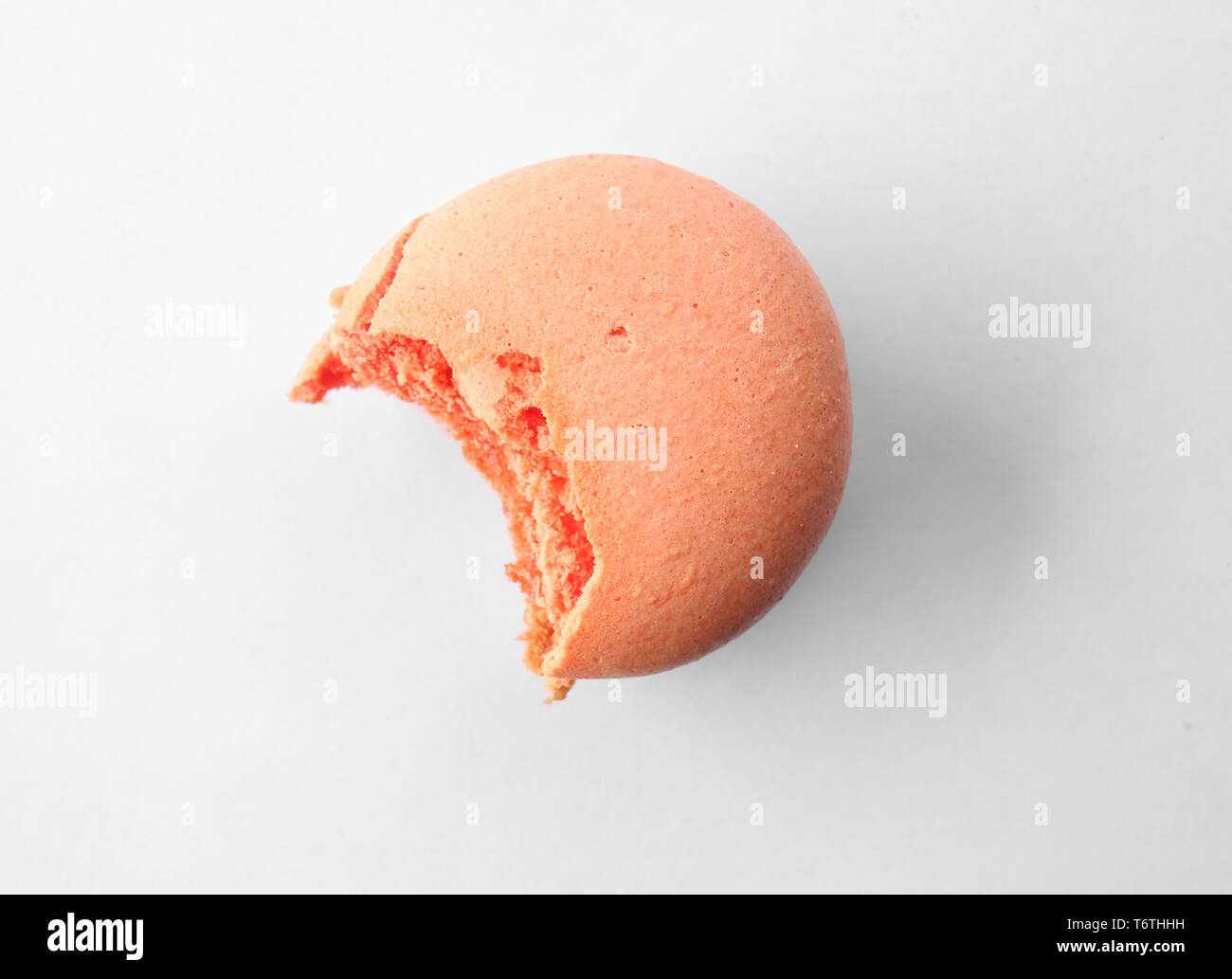 Tasty orange macaron with bite mark on white background Stock Photo - Alamy