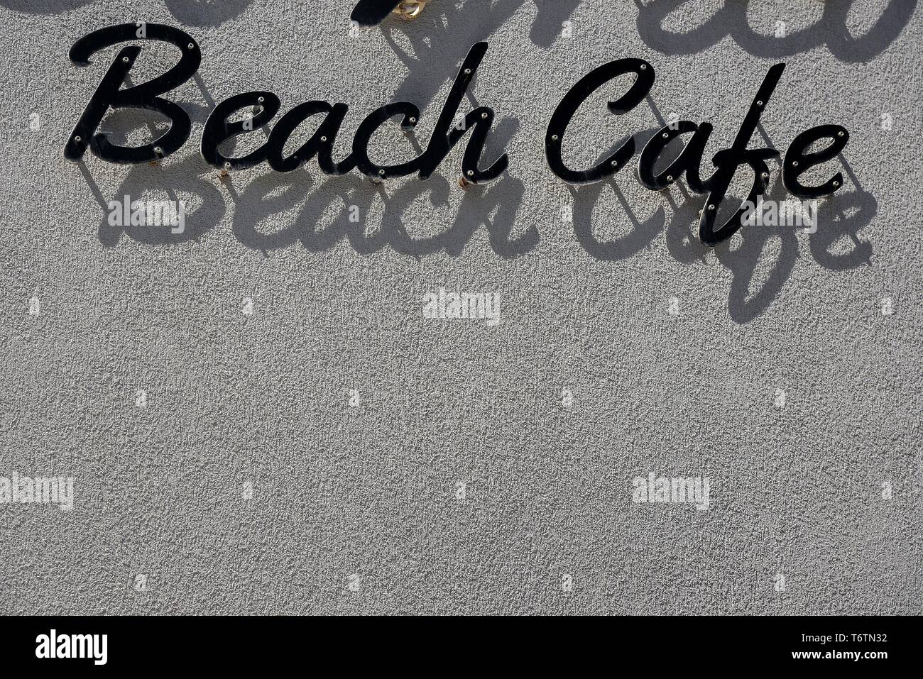 Beach cafe sign casting shadows on grey wall Stock Photo - Alamy