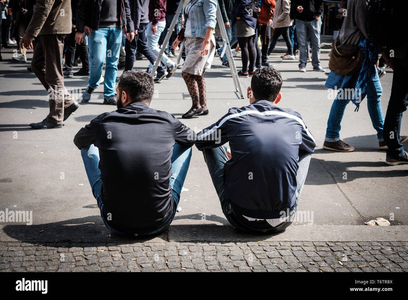 Two men sitting on sidewalk from behind Stock Photo - Alamy