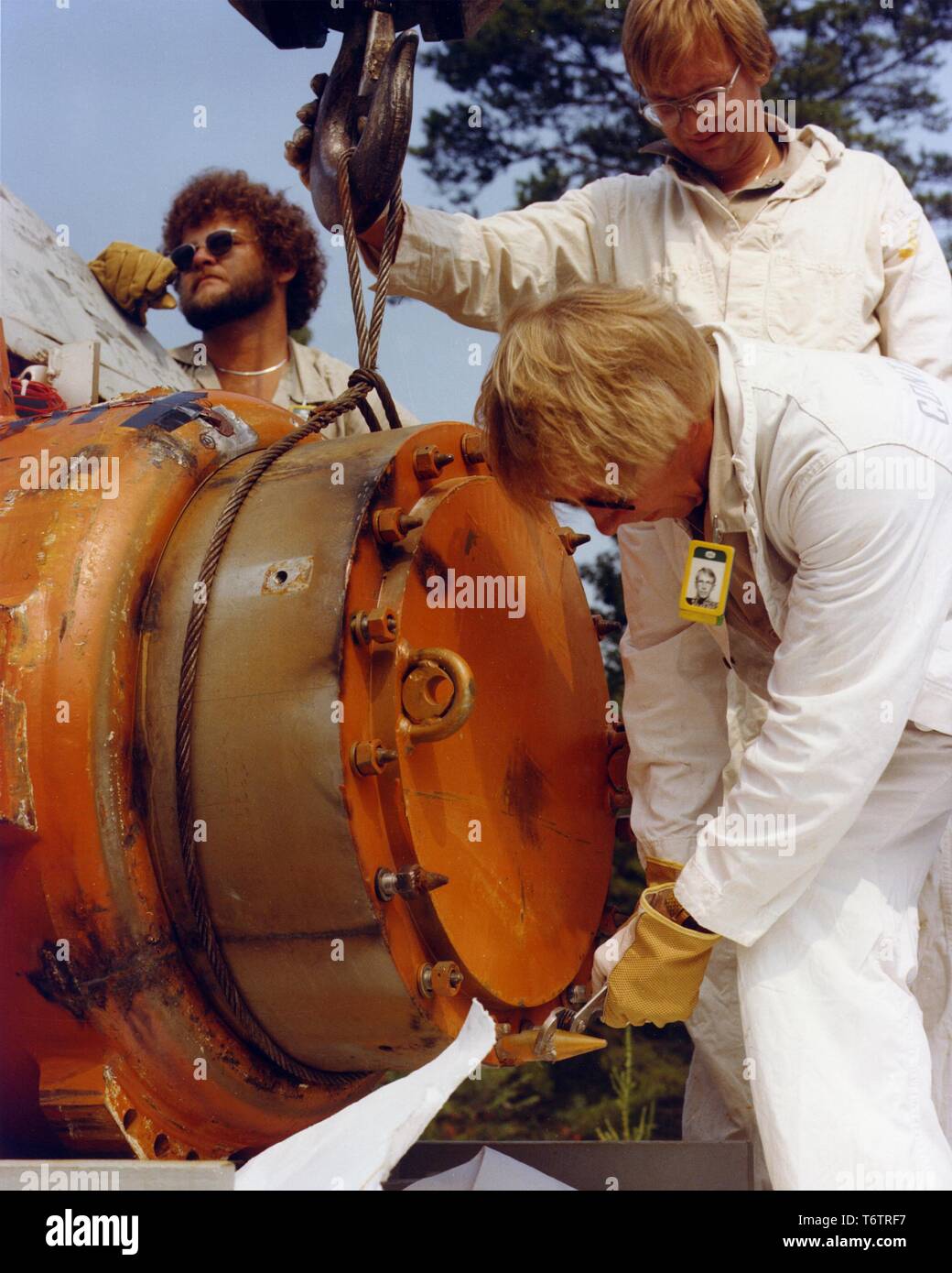 Workers wearing protective gear remove the closure end of a 22-ton ...