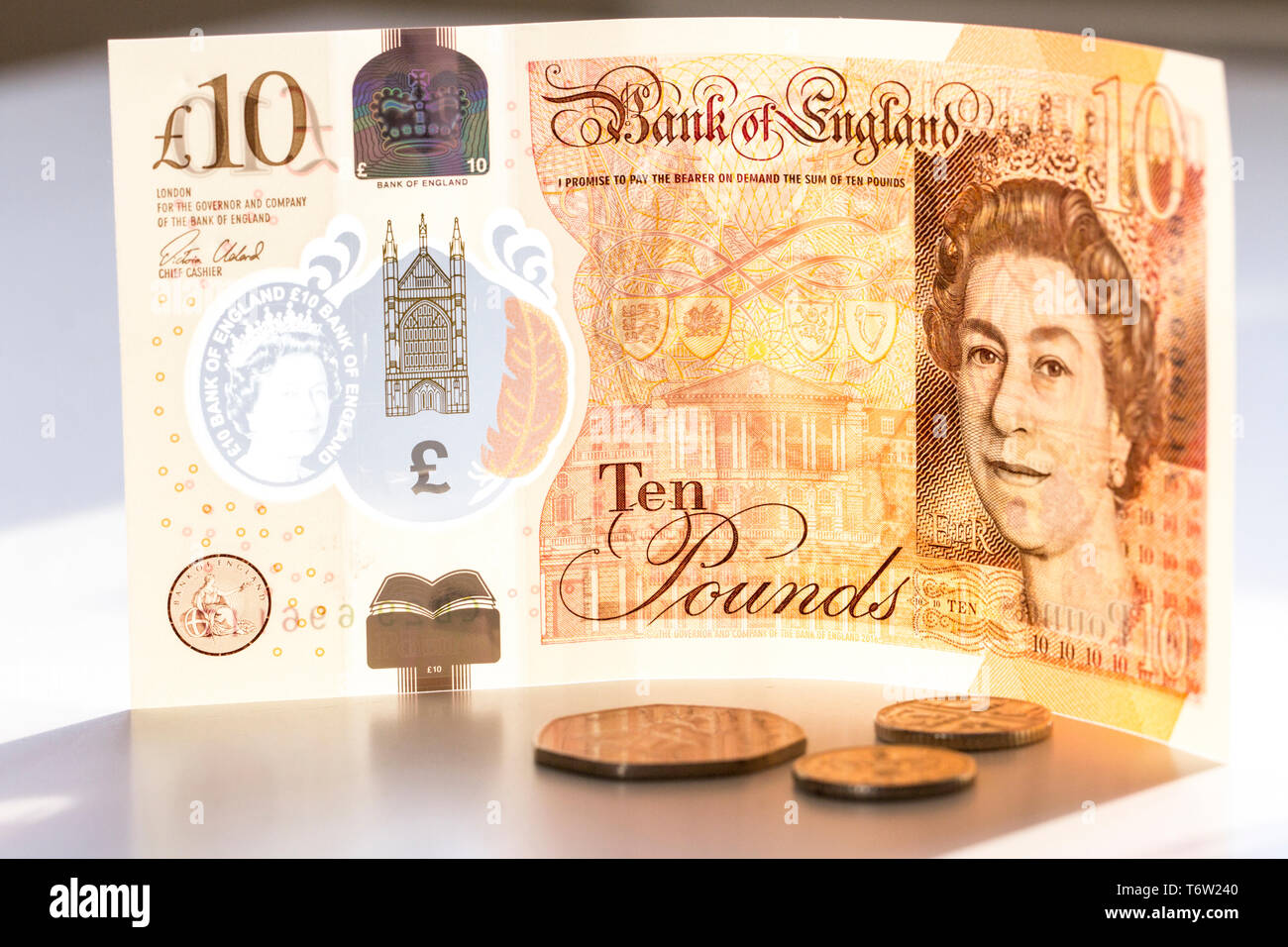 Close-up photo of a piece of new £10 banknote and pence coins. Ten ...