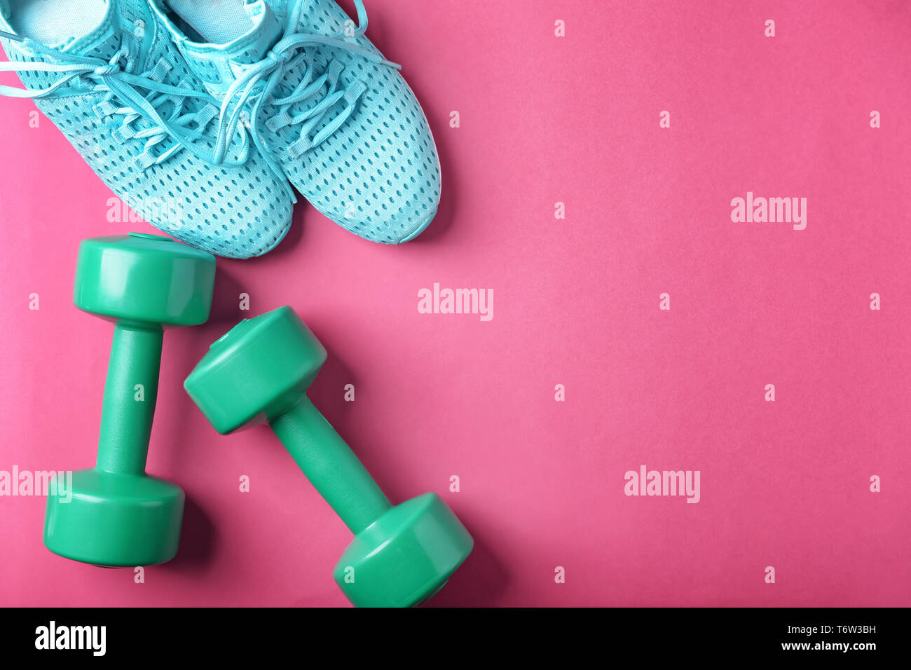 Flat lay composition with sneakers and dumbbells on color background ...