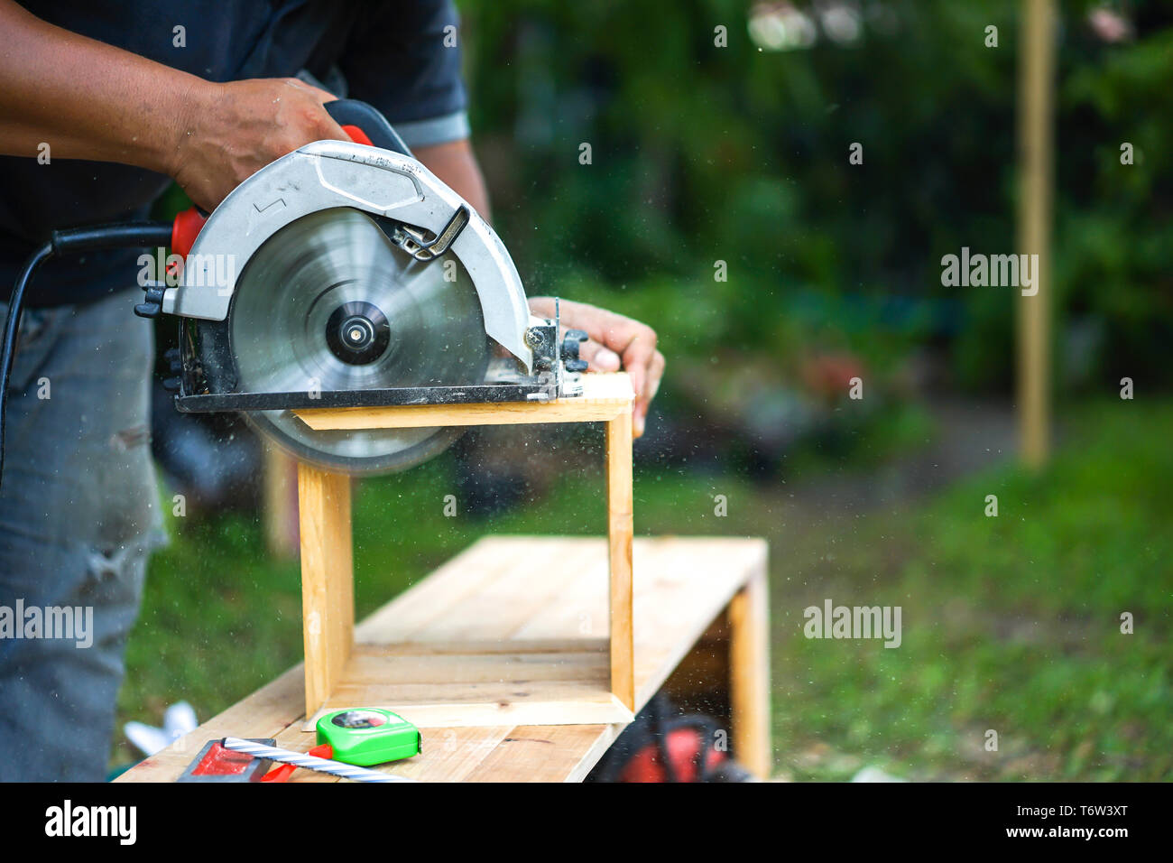 Asian carpenter are sawing the wood in the backyard garden at home ...