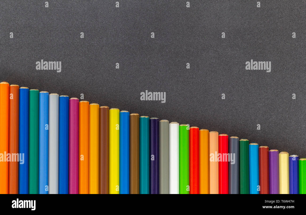 Diagonal line of colored pencils bottom side dark background top view ...