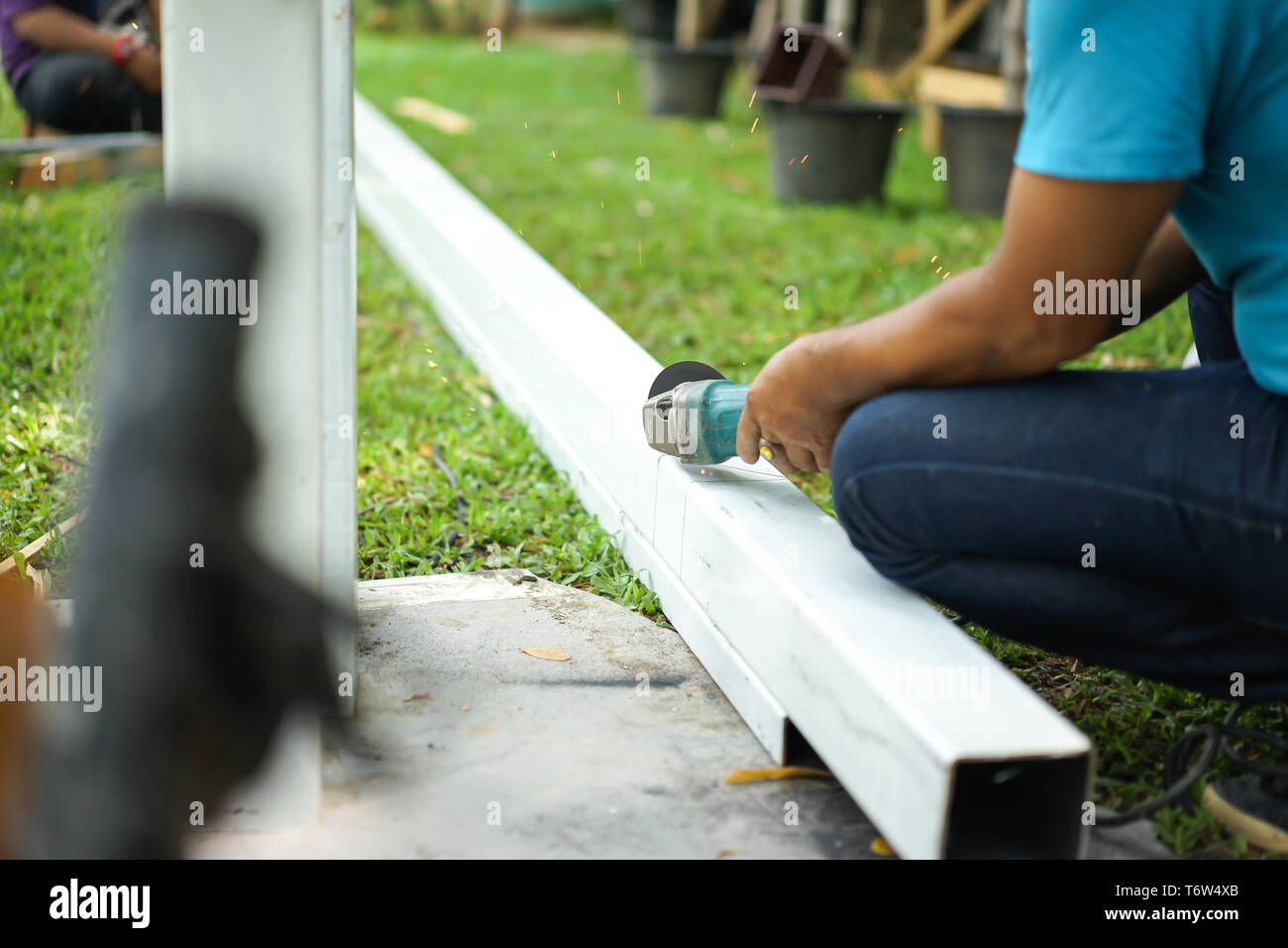 Asian smith worker are sawing the steel / iron pole in the backyard ...