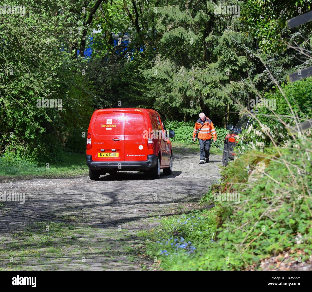 A postal worker on his way back to his van after delivering to a house ...