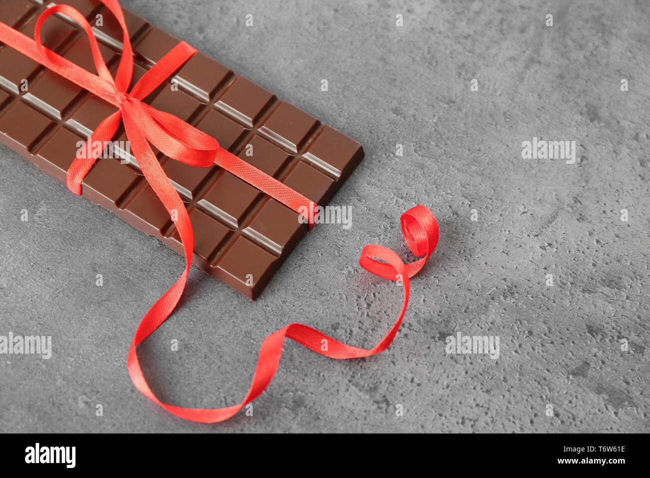 Chocolate bar with color ribbon on grey background Stock Photo - Alamy