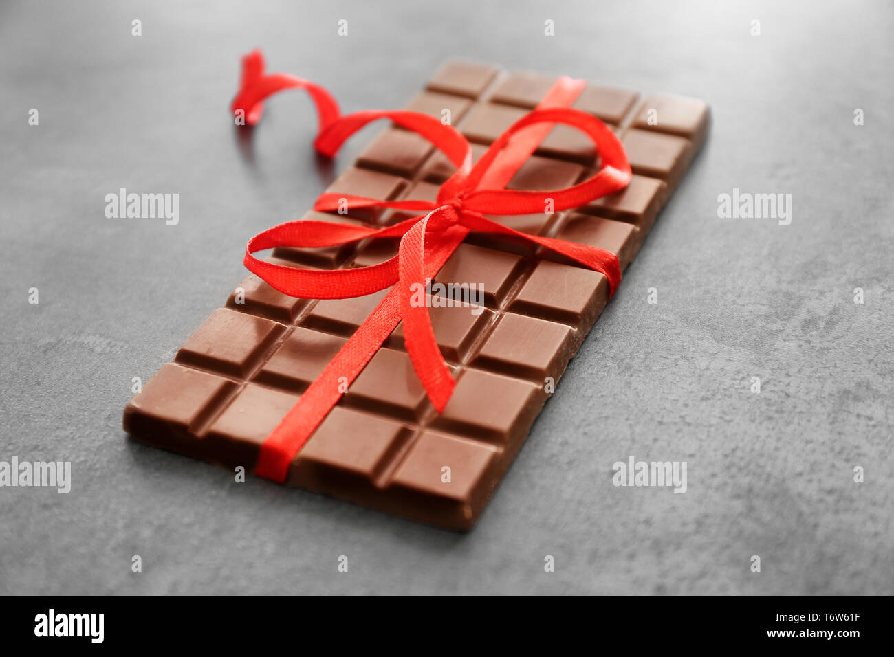 Chocolate bar with color ribbon on grey background Stock Photo - Alamy