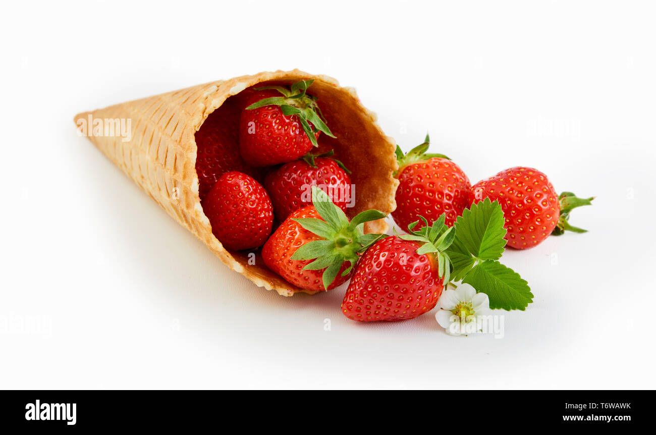 Cornet wafer ice cream cone with fresh ripe red strawberries spilling ...