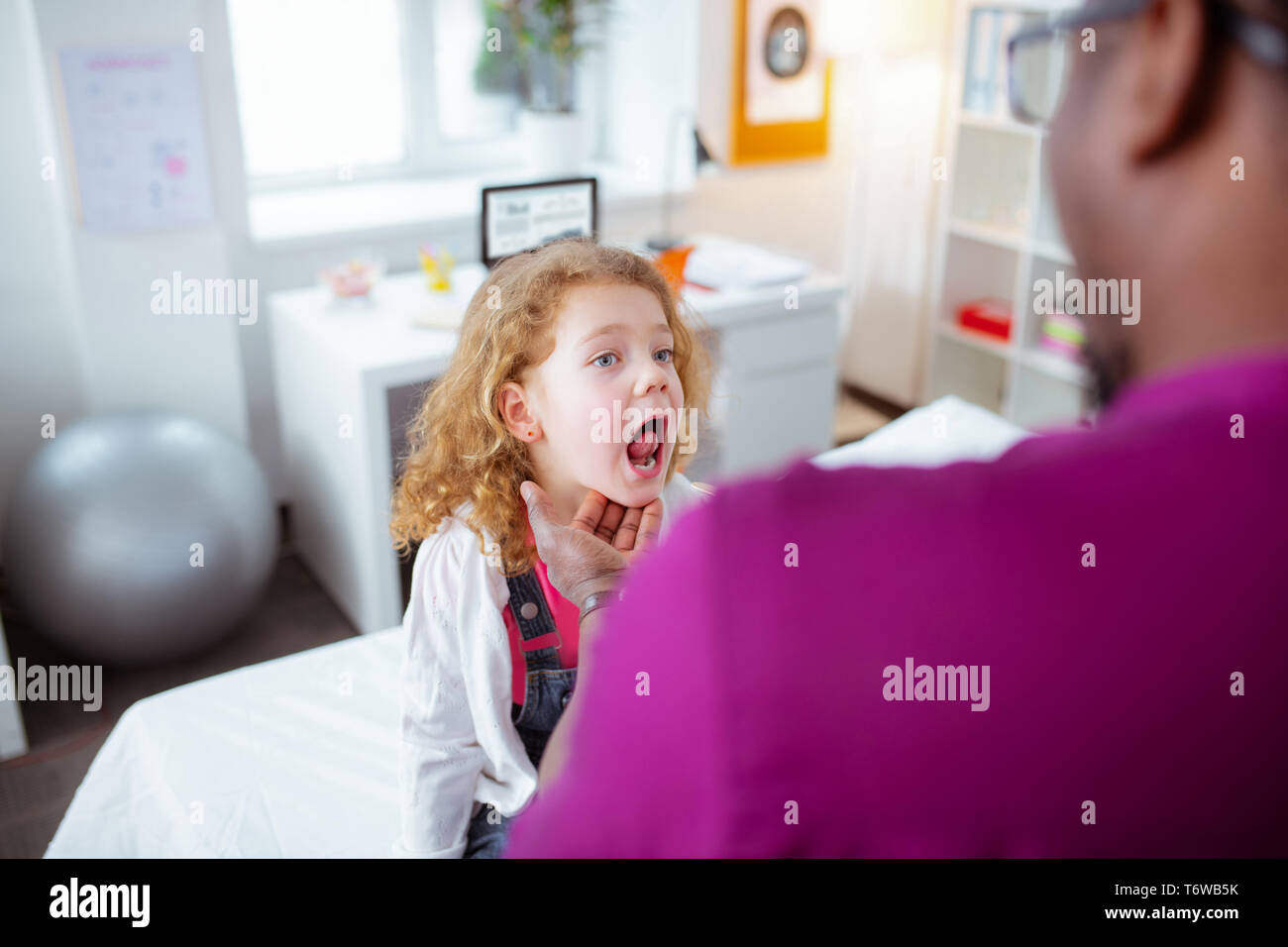 Girl opening mouth showing her throat while visiting doctor Stock Photo ...