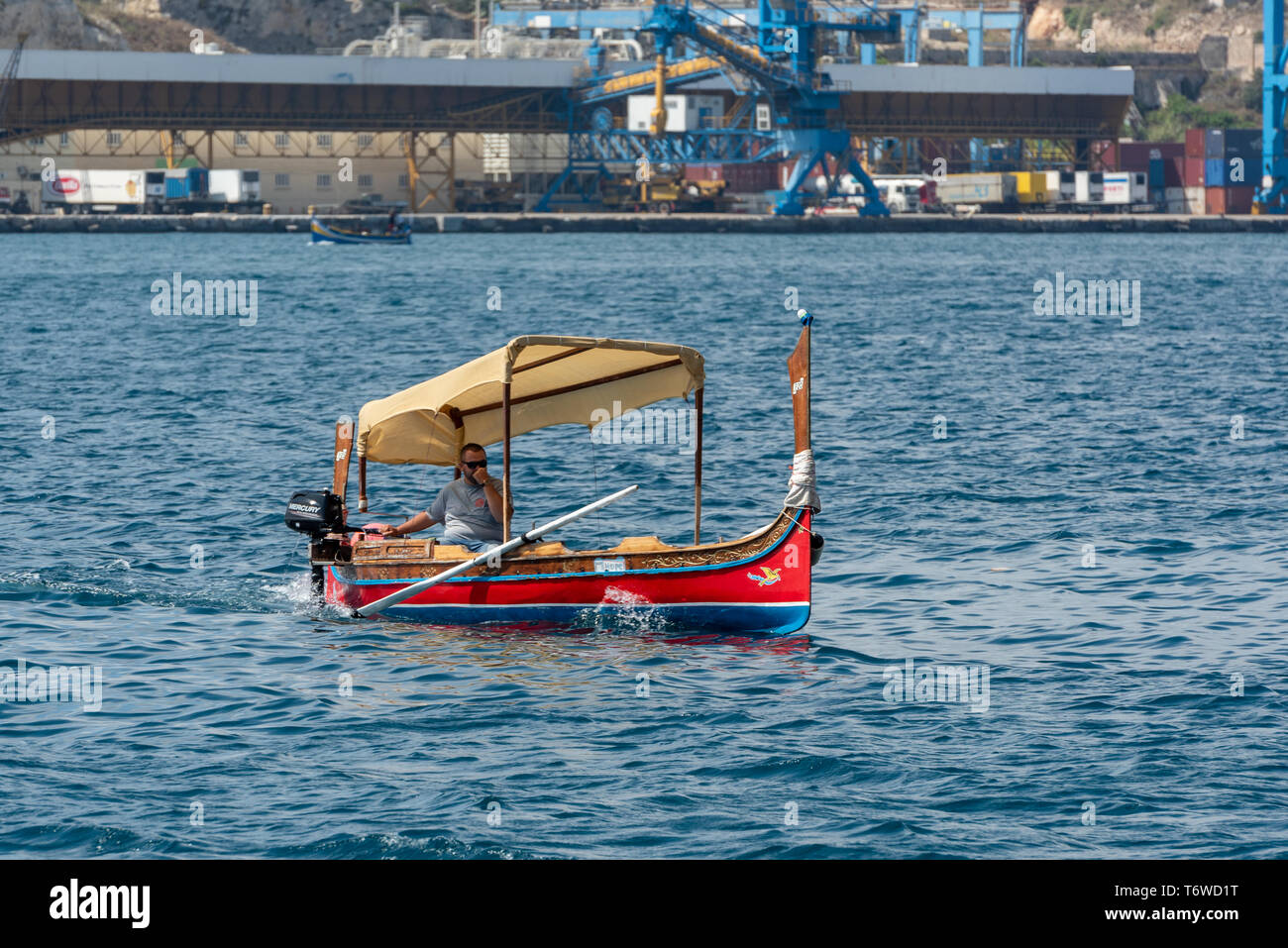 A colourful Dghajsa tal-Pass, traditional Maltese boat, crossing ...