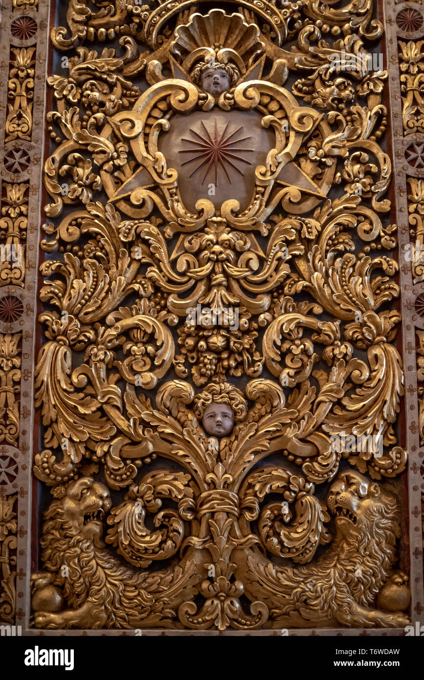 An intricately carved stone cartouche covered in gilded motifs of ...
