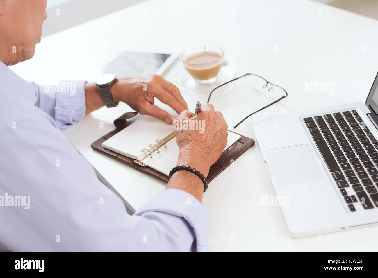 Asian senior man taking some notes while sitting Stock Photo - Alamy