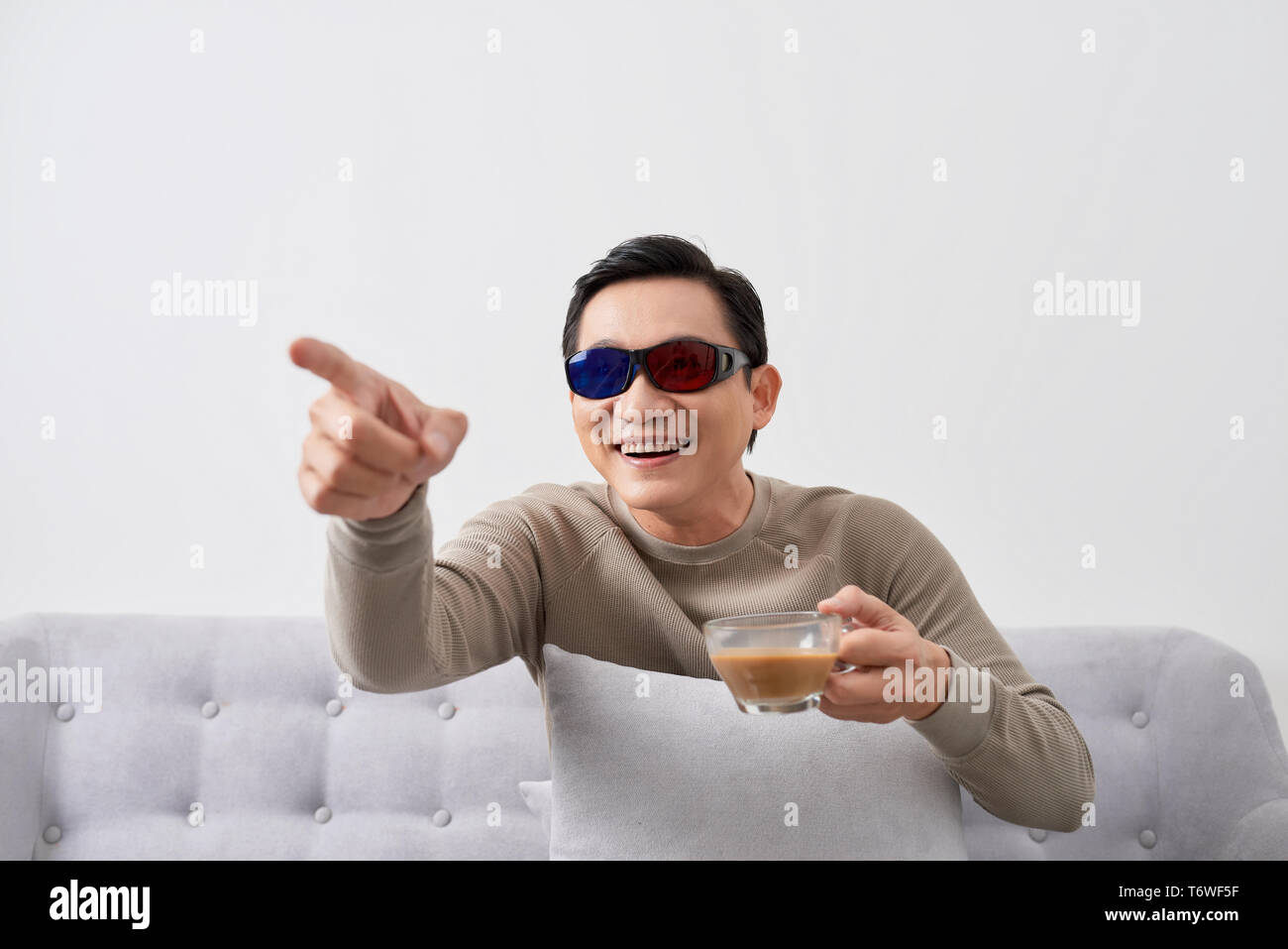 exciting young man watch three-dimensional LCD TV with eye glass in a ...