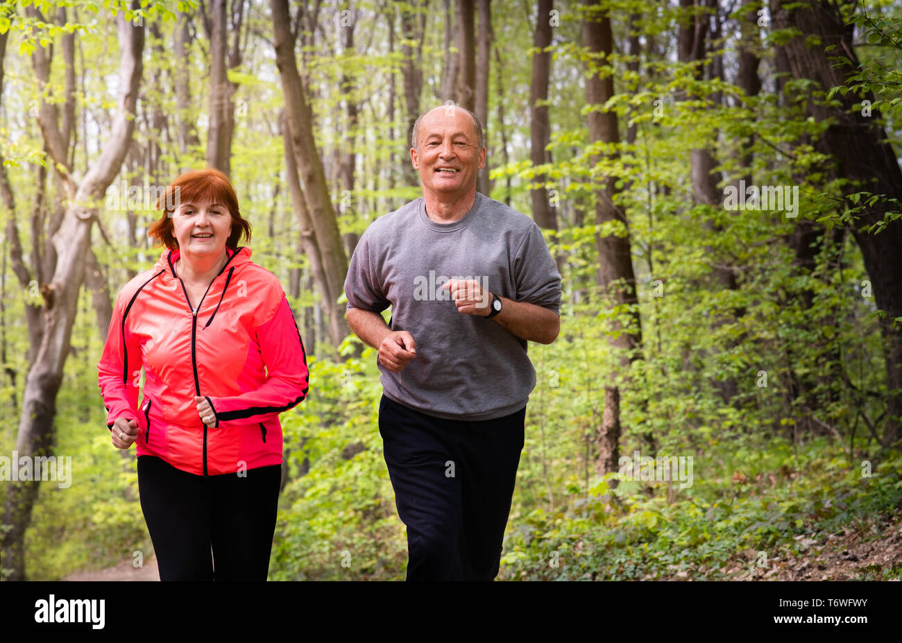 Husband and wife wearing sportswear and running in forest at mountain ...