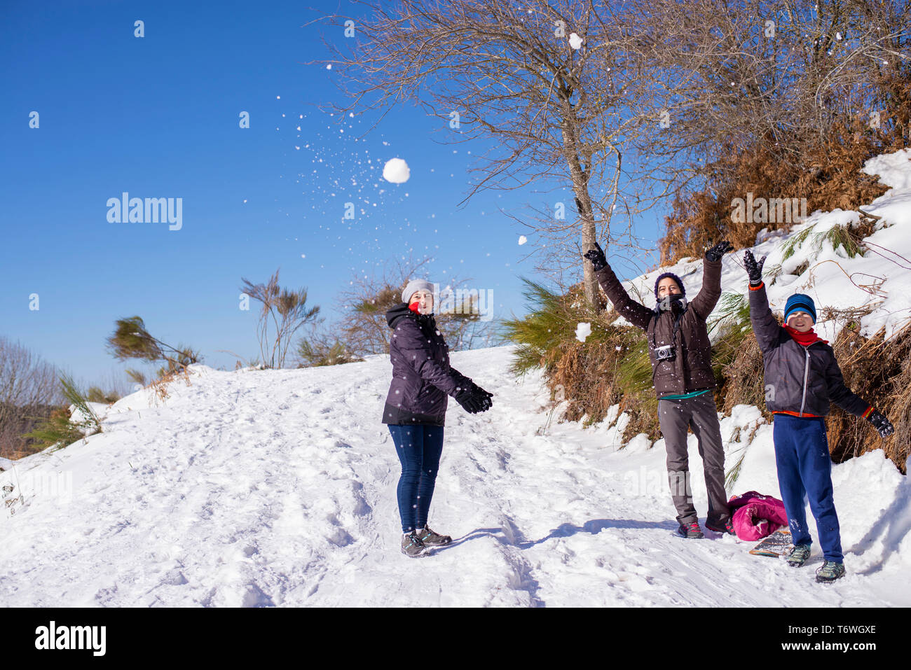 Three people throwing snowballs while standing on a covered gateway ...
