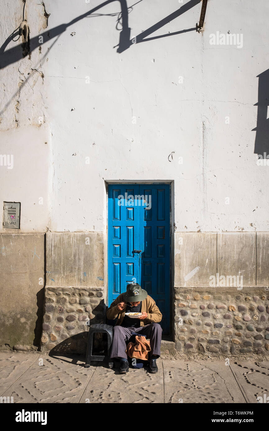 Man sitting and eating on a door thershold in the streets of ...