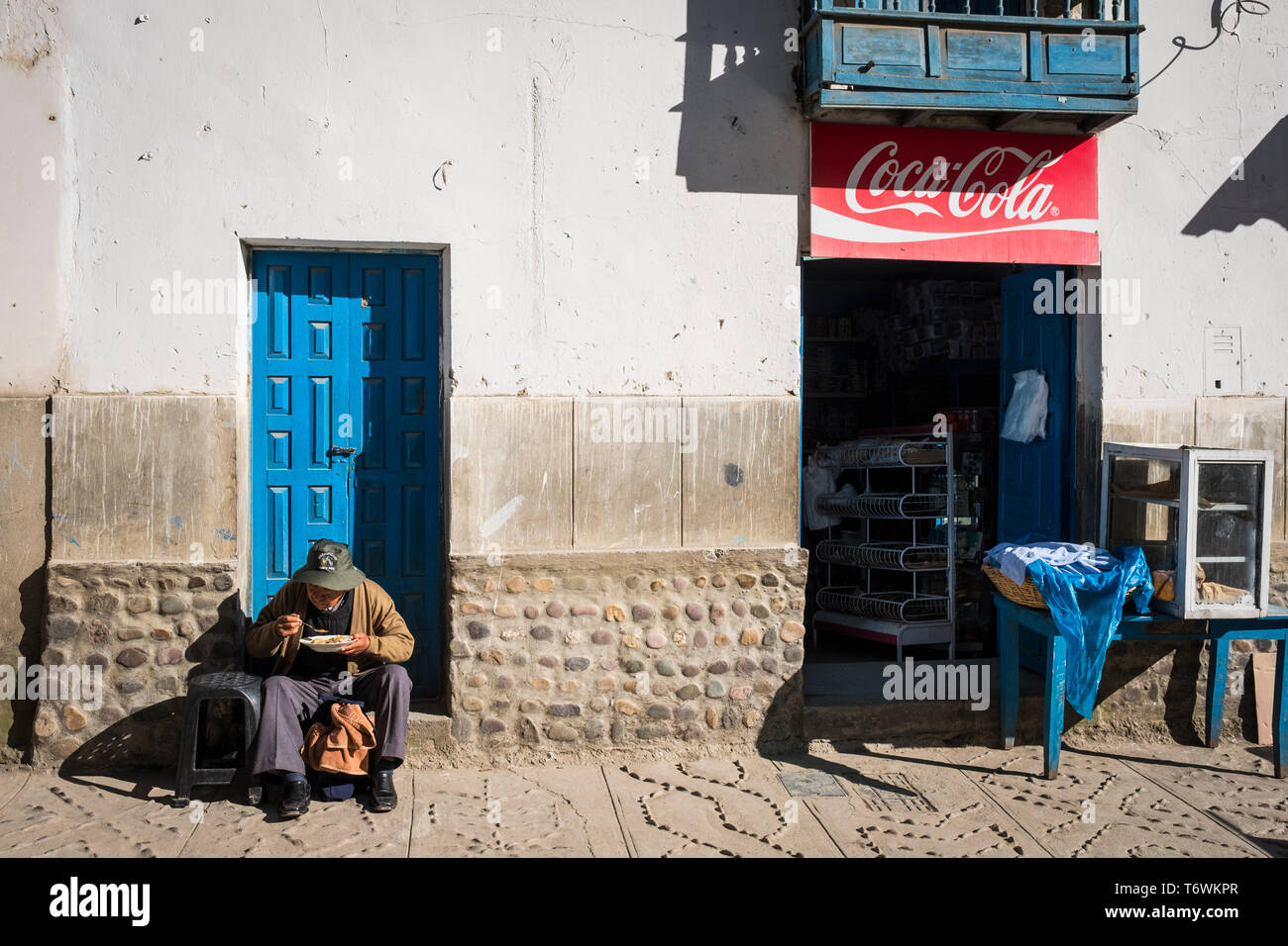 Man sitting and eating on a door thershold in the streets of ...