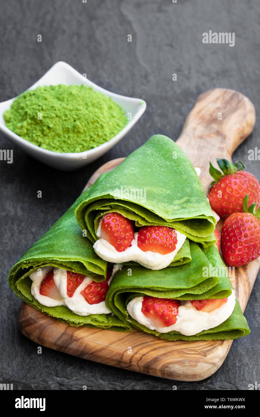 Matcha green tea crepe with whipped cream and strawberry on serving ...