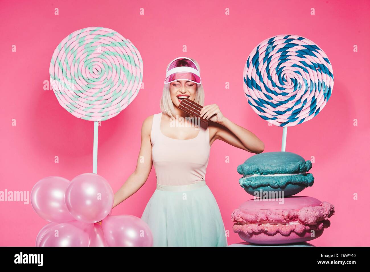 Beautiful girl posing with sweets at pink background Stock Photo - Alamy