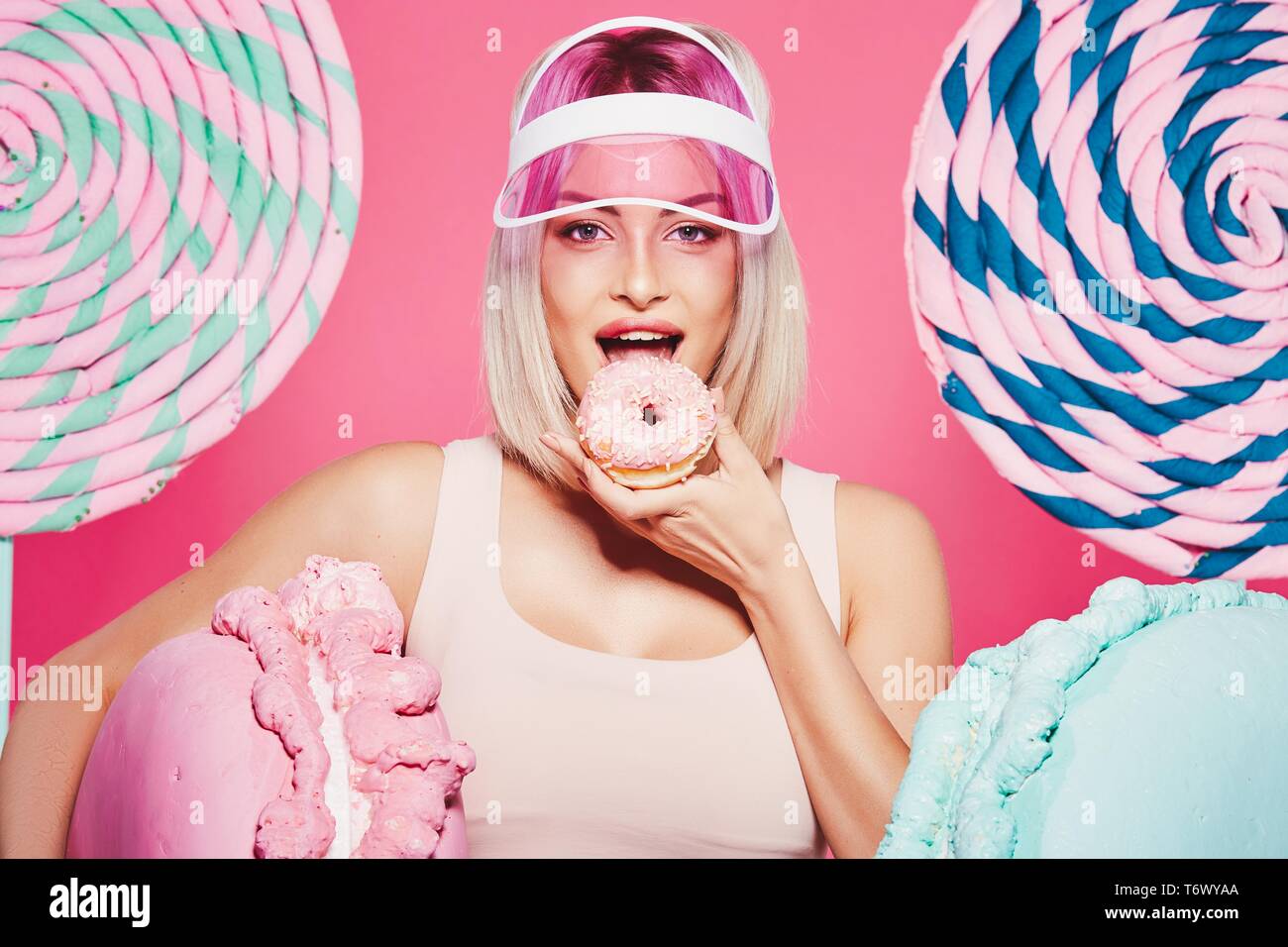 Beautiful girl posing with sweets at pink background Stock Photo - Alamy