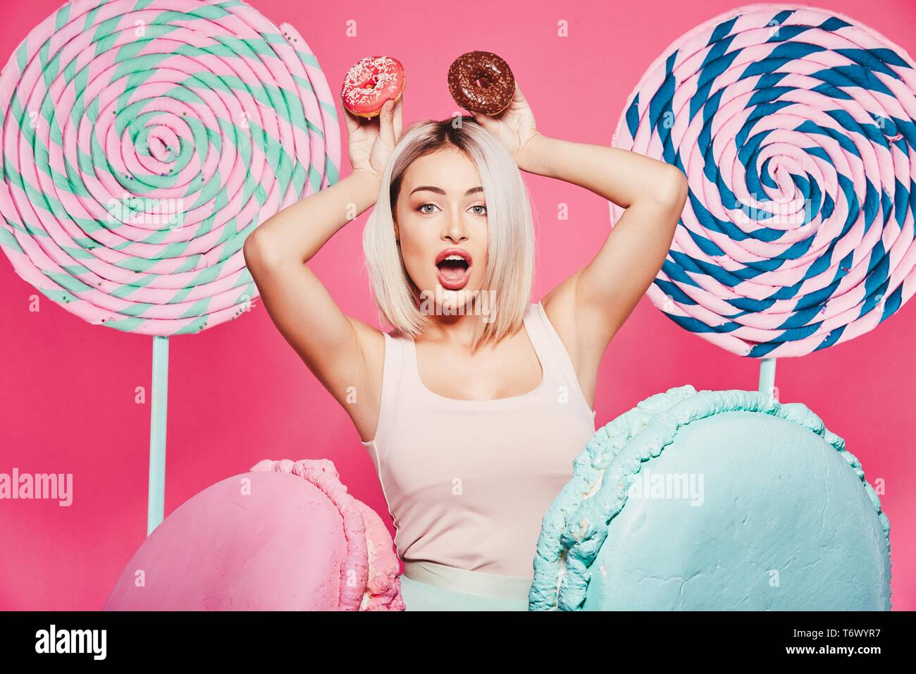Beautiful girl posing with sweets at pink background Stock Photo - Alamy