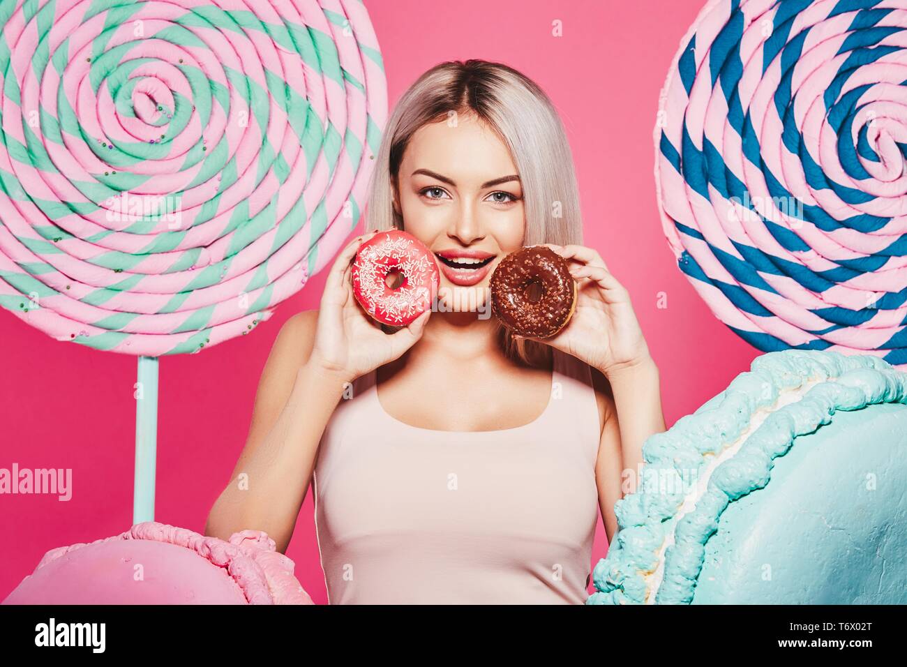 Beautiful girl posing with sweets at pink background Stock Photo - Alamy
