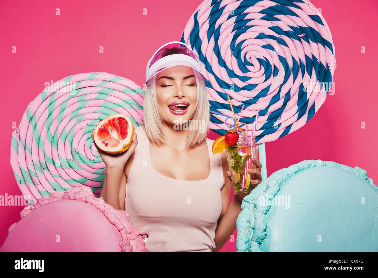 Beautiful girl posing with sweets at pink background Stock Photo - Alamy