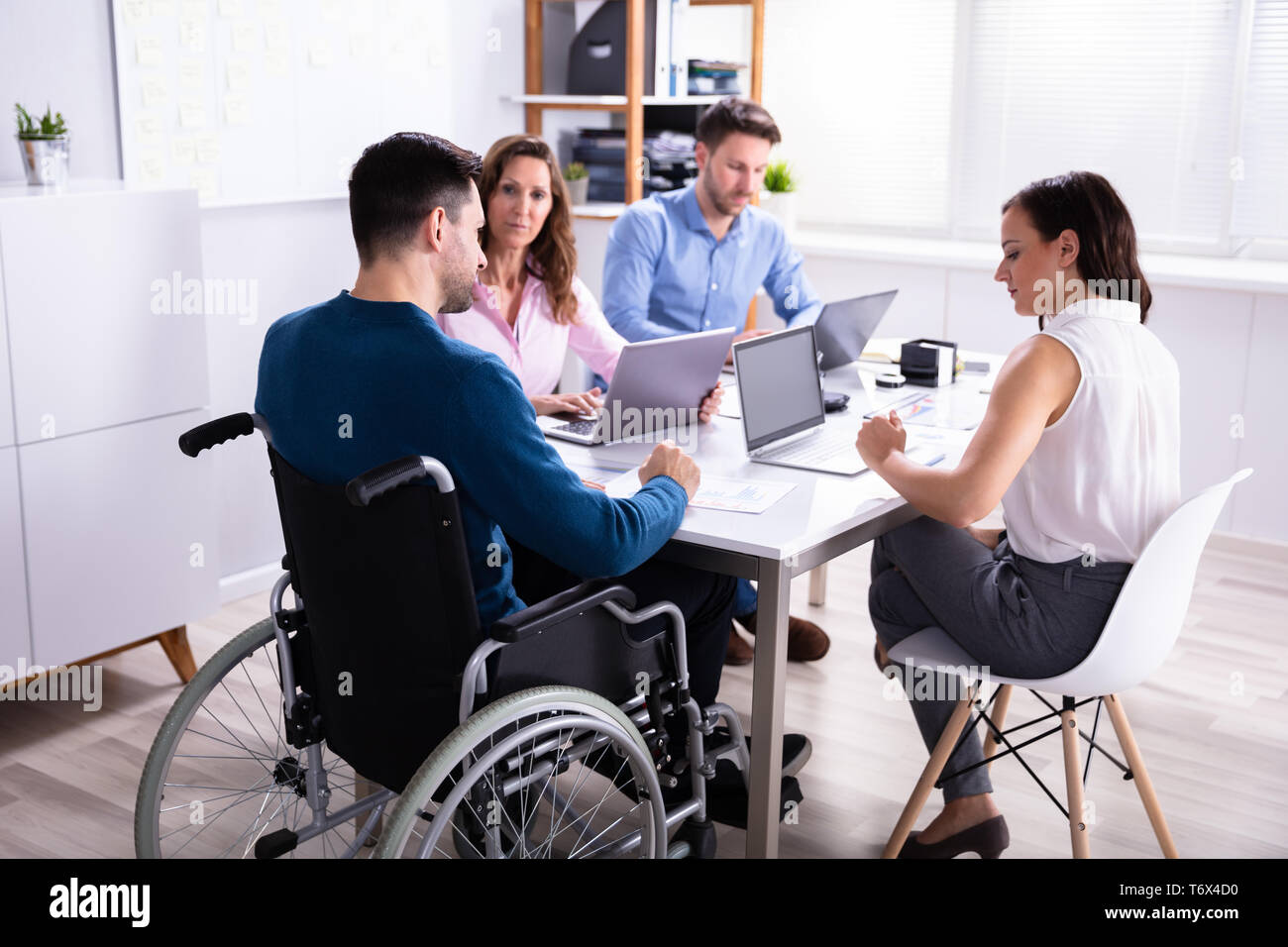 Disabled Male Manager Sitting With His Colleagues At Workplace Stock ...