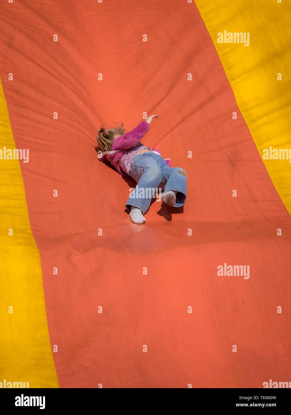 Girl sliding down on a big inflatable slide Stock Photo - Alamy