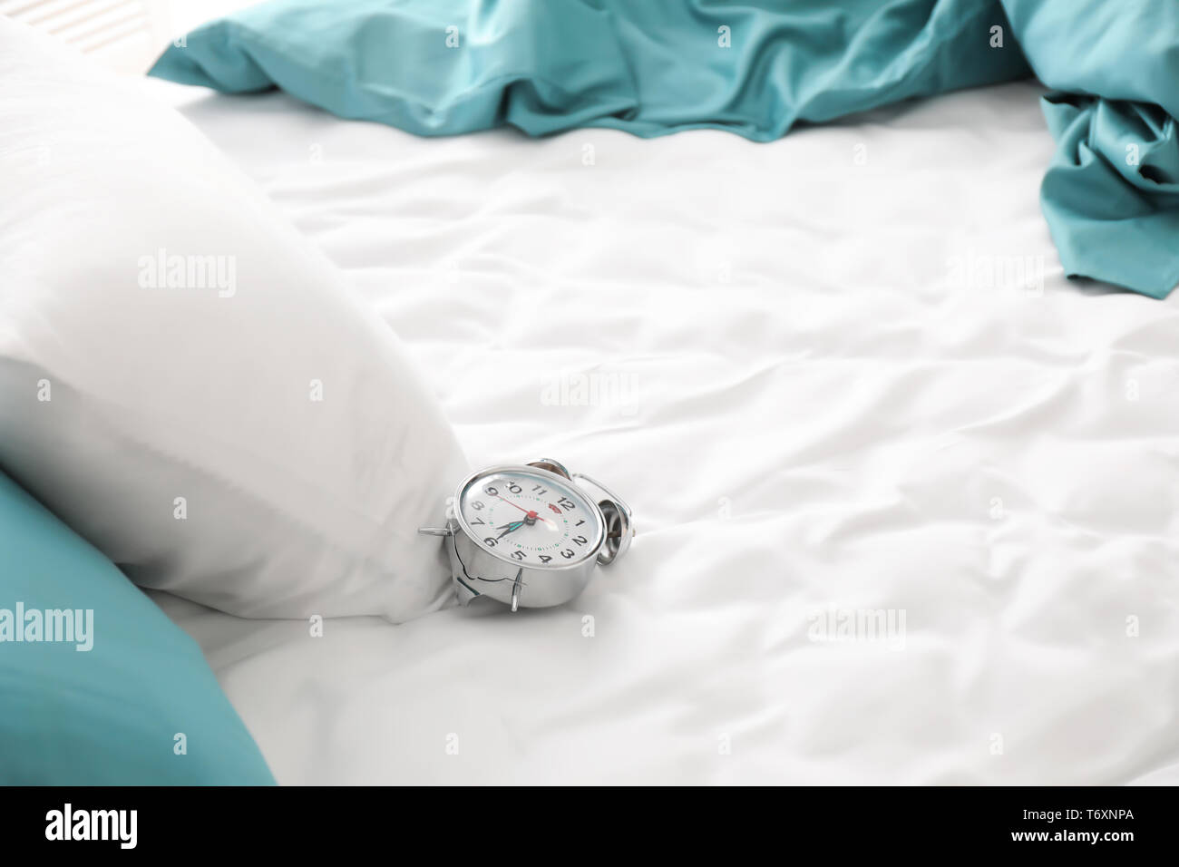 Alarm clock on empty bed Stock Photo - Alamy