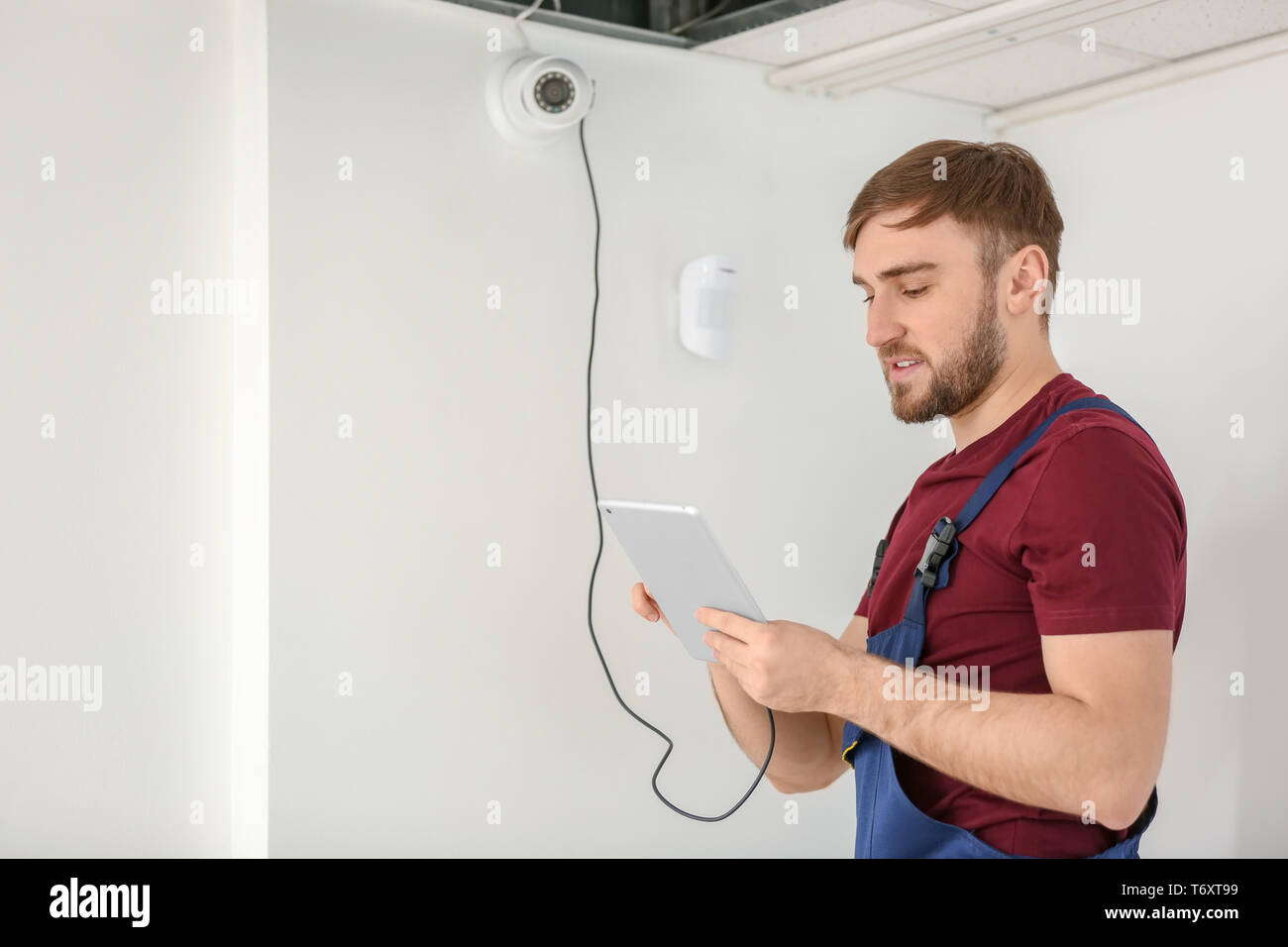 Electrician installing security camera indoors Stock Photo - Alamy